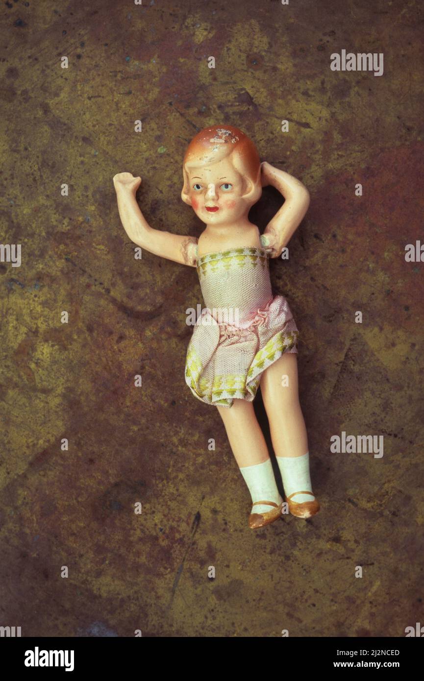 1920s girl doll lying on tarnished brass with arms stretching up Stock ...