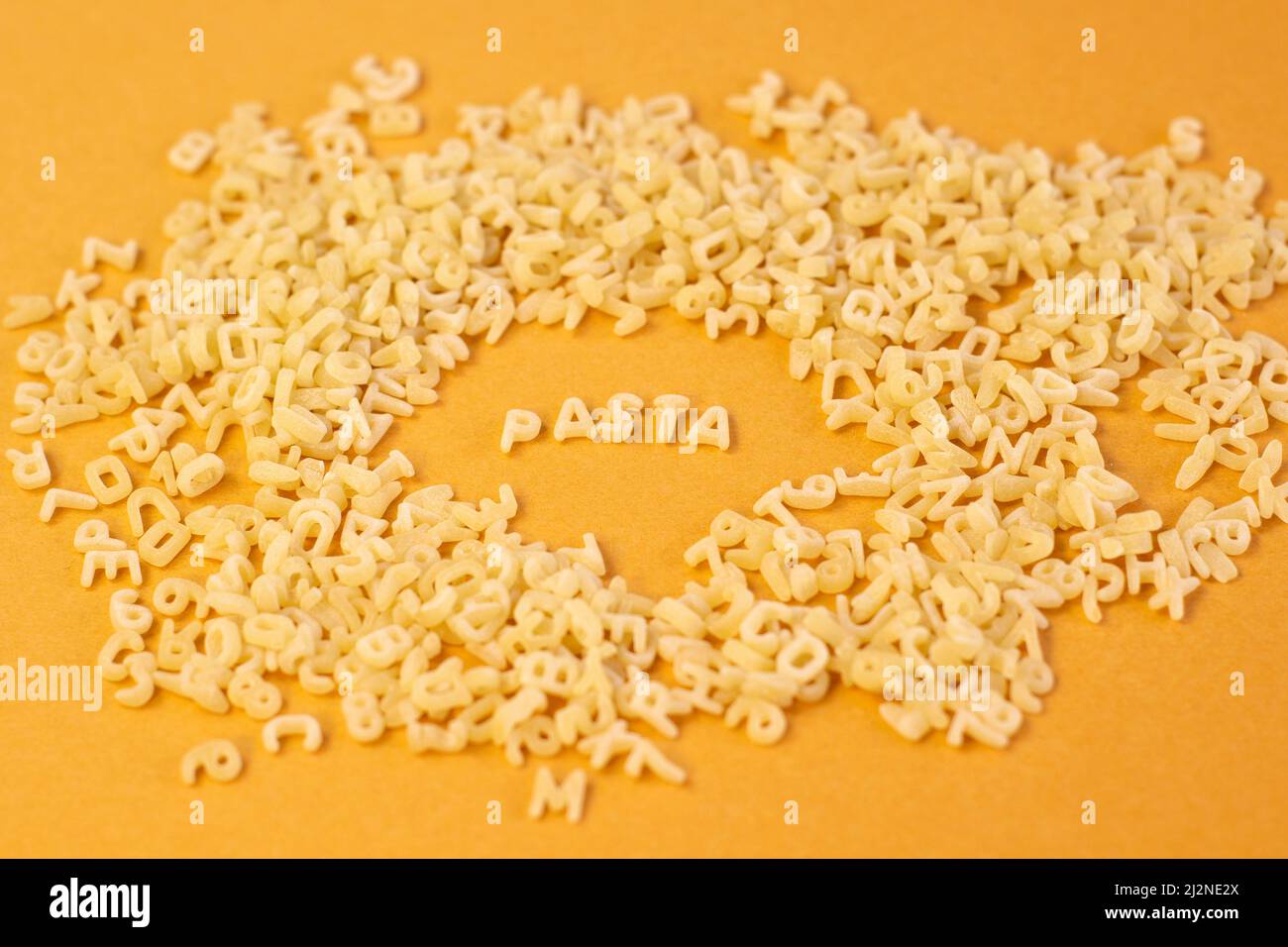 Whole grain dark pasta letters on dark yellow textured background front ...