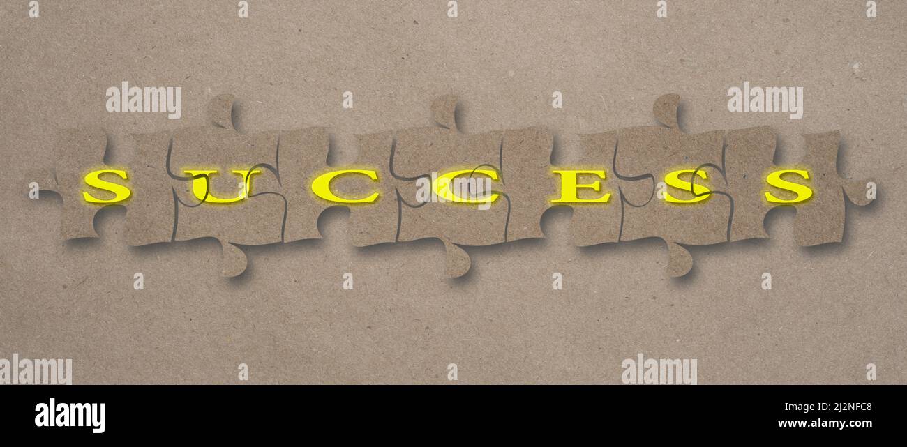 Success word assembled on puzzle pieces against a craft paper ...