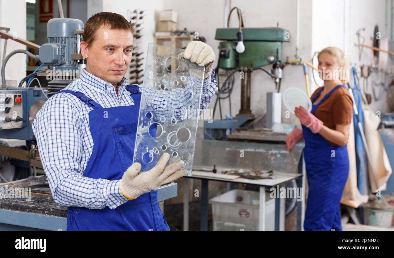 Male glazier working with glass on drilling machine Stock Photo - Alamy