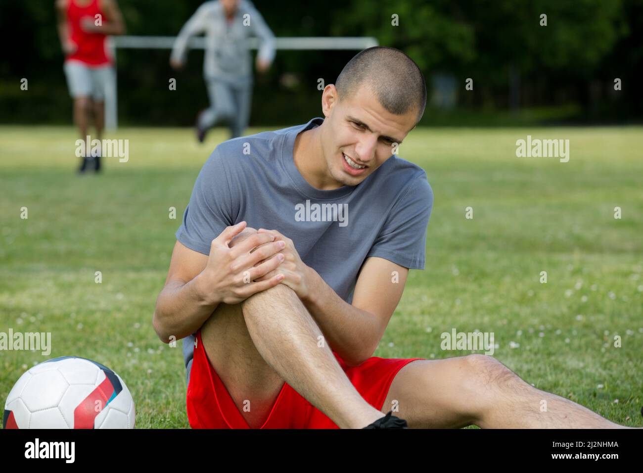 male player suffering from knee injury lying on field Stock Photo - Alamy