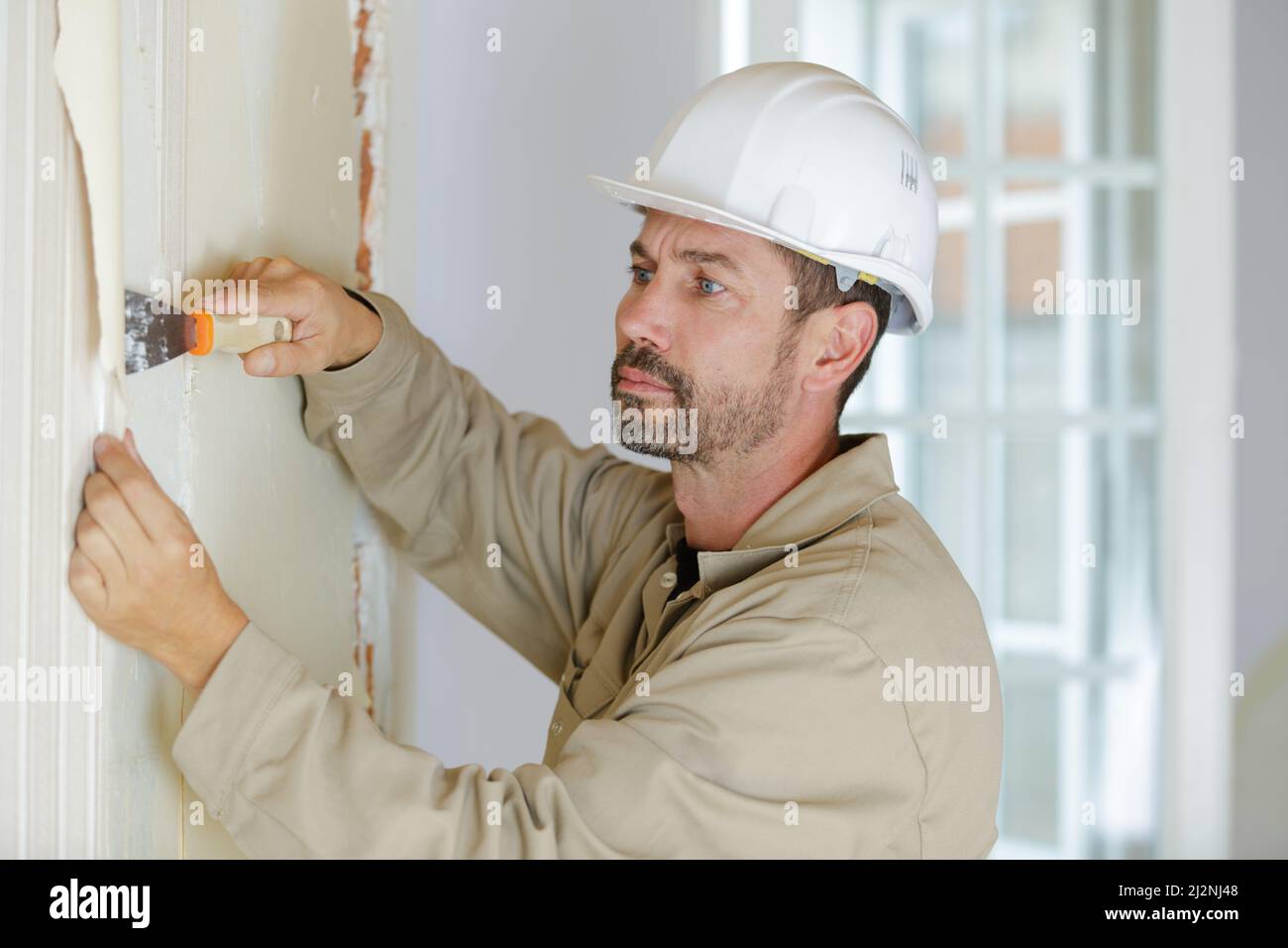professional male builder stripping wallpaper Stock Photo - Alamy