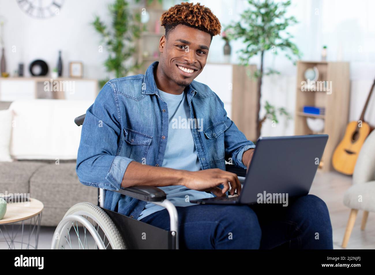 man sitting in wheelchair using laptop in office Stock Photo - Alamy