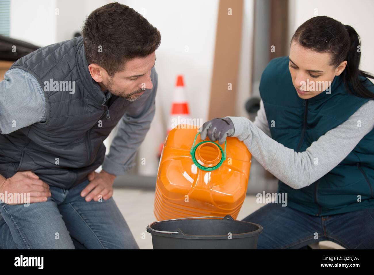 male and female workers pouring liquid in bucket Stock Photo - Alamy