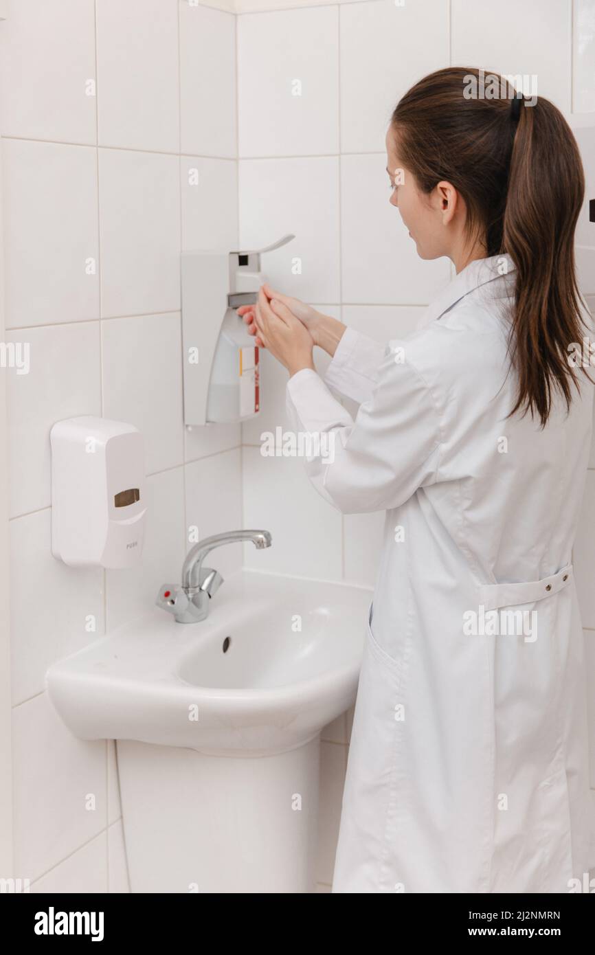 The doctor in white uniform disinfects his hands. Surgeon washing hands ...