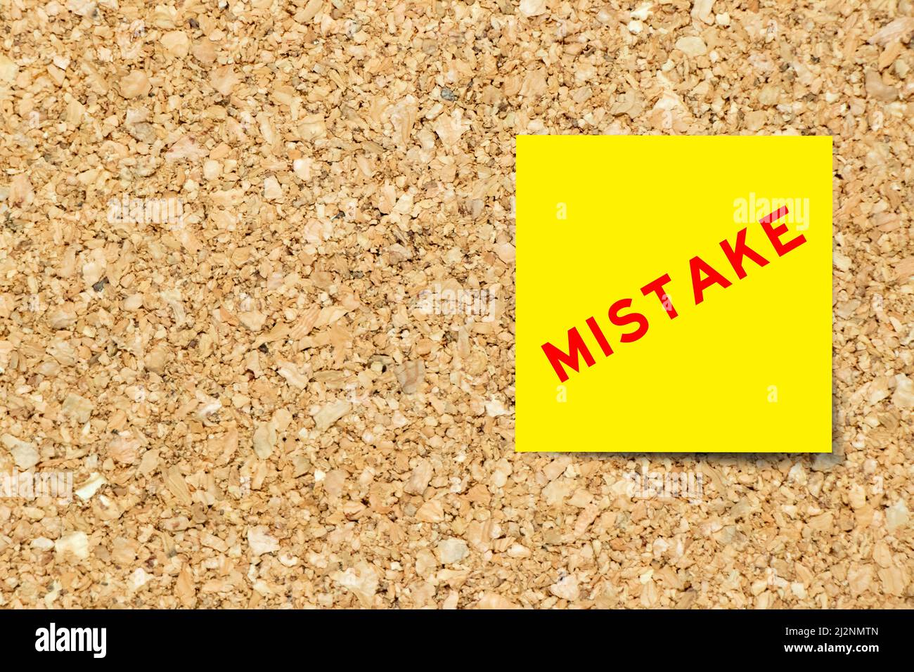Yellow note paper with word mistake on cork board background with copy ...