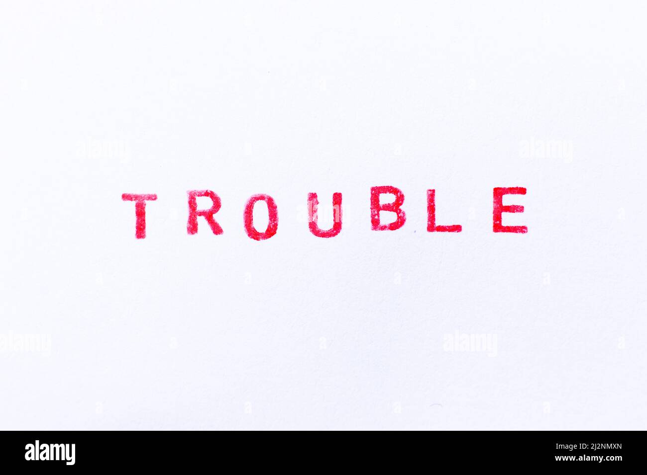 Red color ink rubber stamp in word trouble on white paper background ...