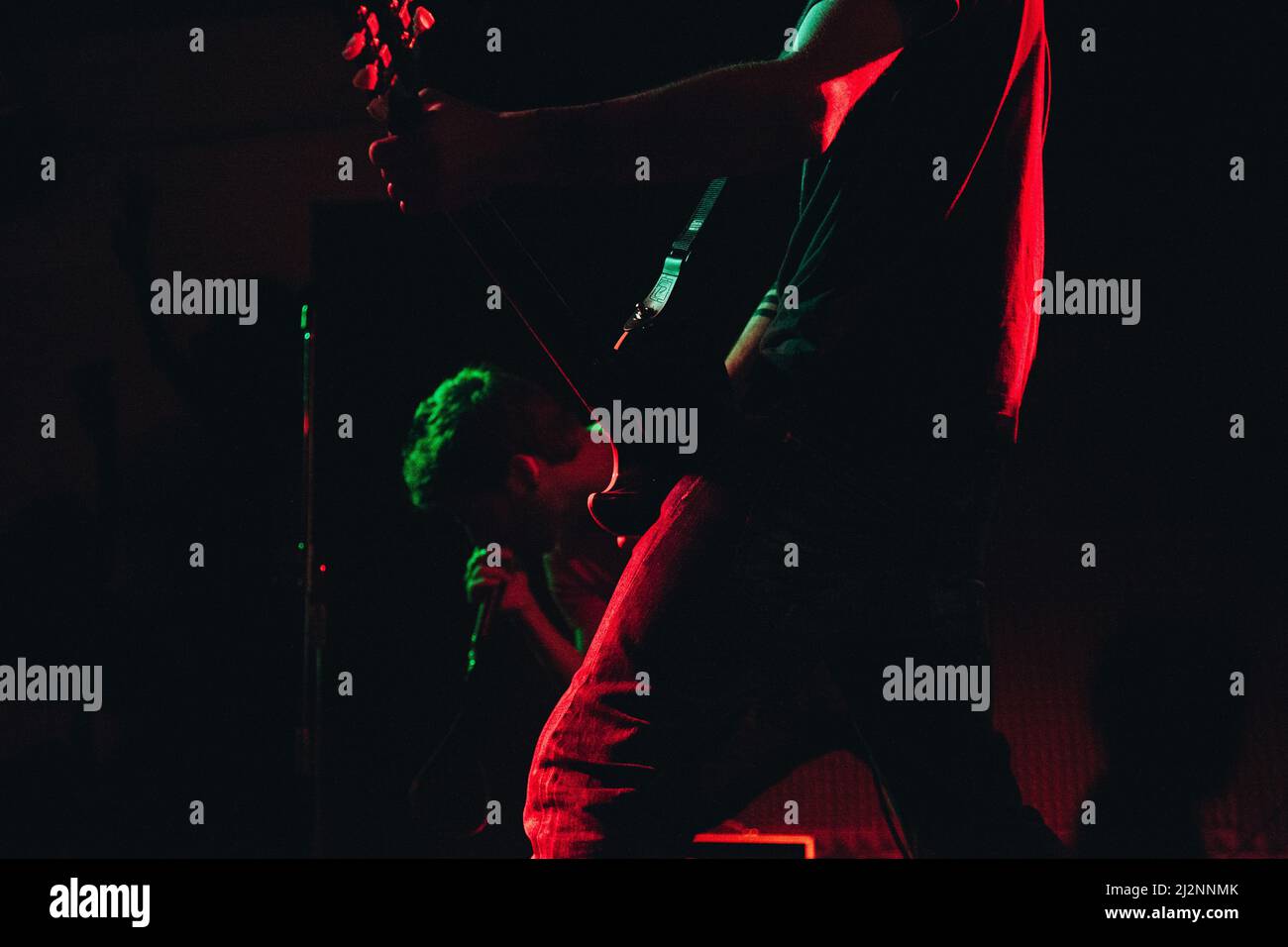 Rock band guitarist performing on stage - vibrant stage red and green ...