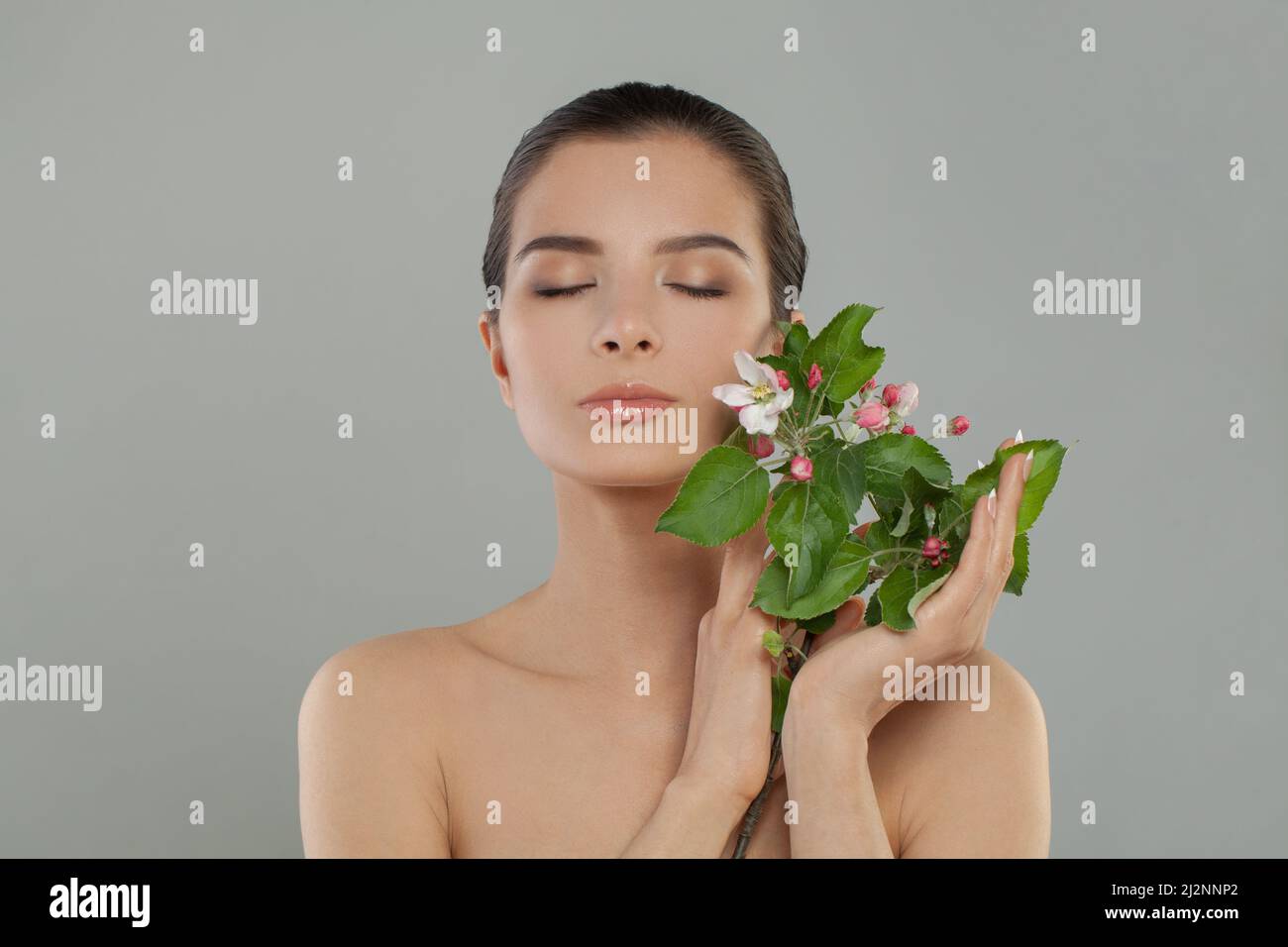 Beautiful female face with flowers. Spring woman relaxing on grey ...
