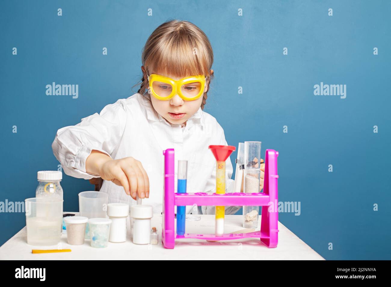Serious school girl doing science experiments on blue background ...