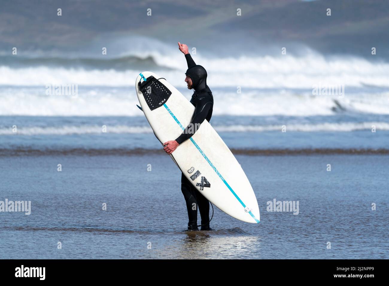 A surfer checks out the waves before entering the water at Putsborough ...