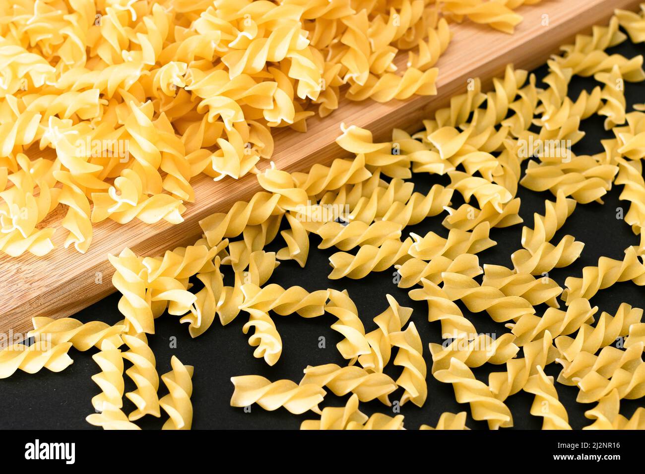 Uncooked Fusilli Pasta Scattered on Wooden Board and Black Table. Raw ...