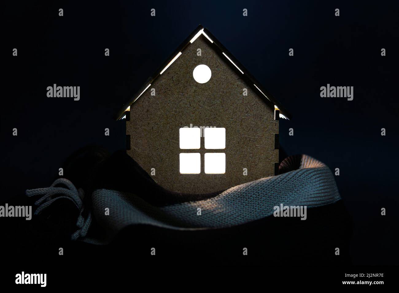 Miniature house model wrapped with a scarf and illuminated from inside ...