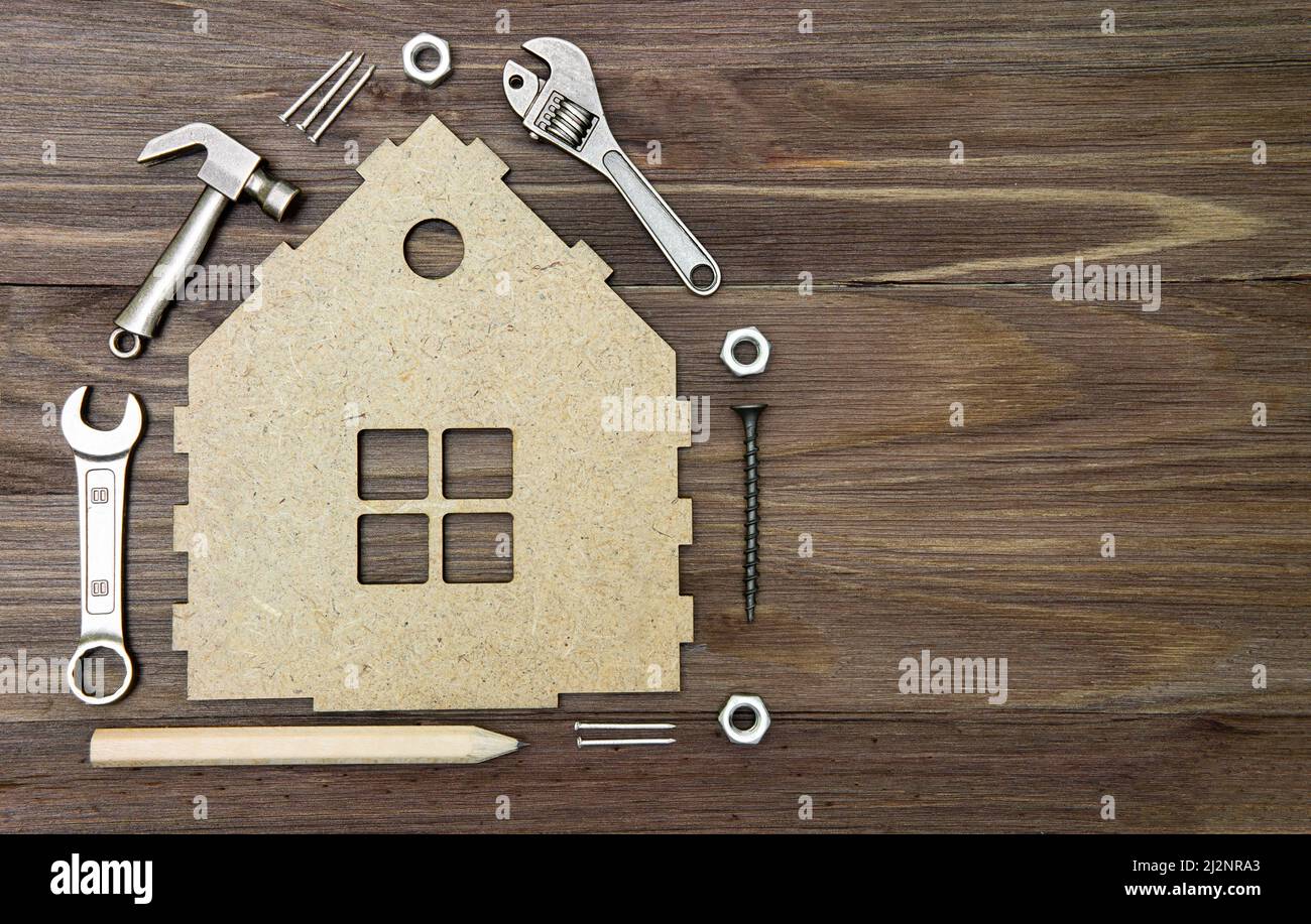 Set of miniature hand tools and fasteners arranged around a flat house ...