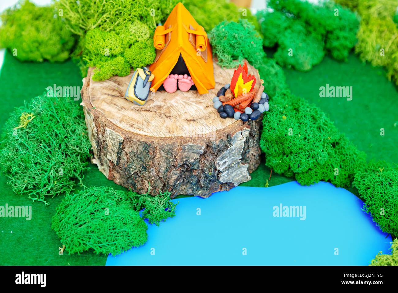 Plasticine landscape with a tent, a fire and a backpack on the lake ...