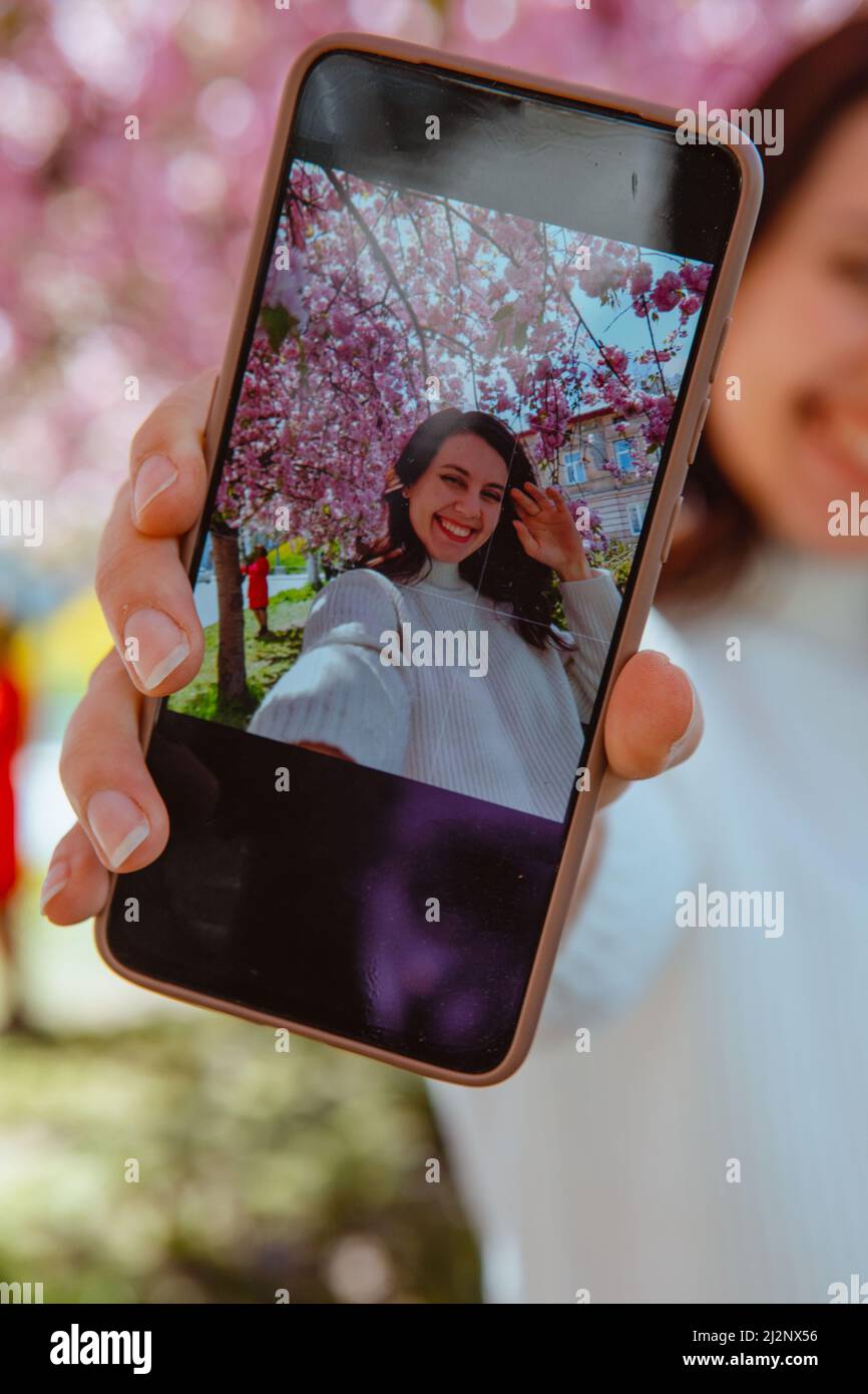 woman shooting her self on the phone under blooming sakura tree selfie ...
