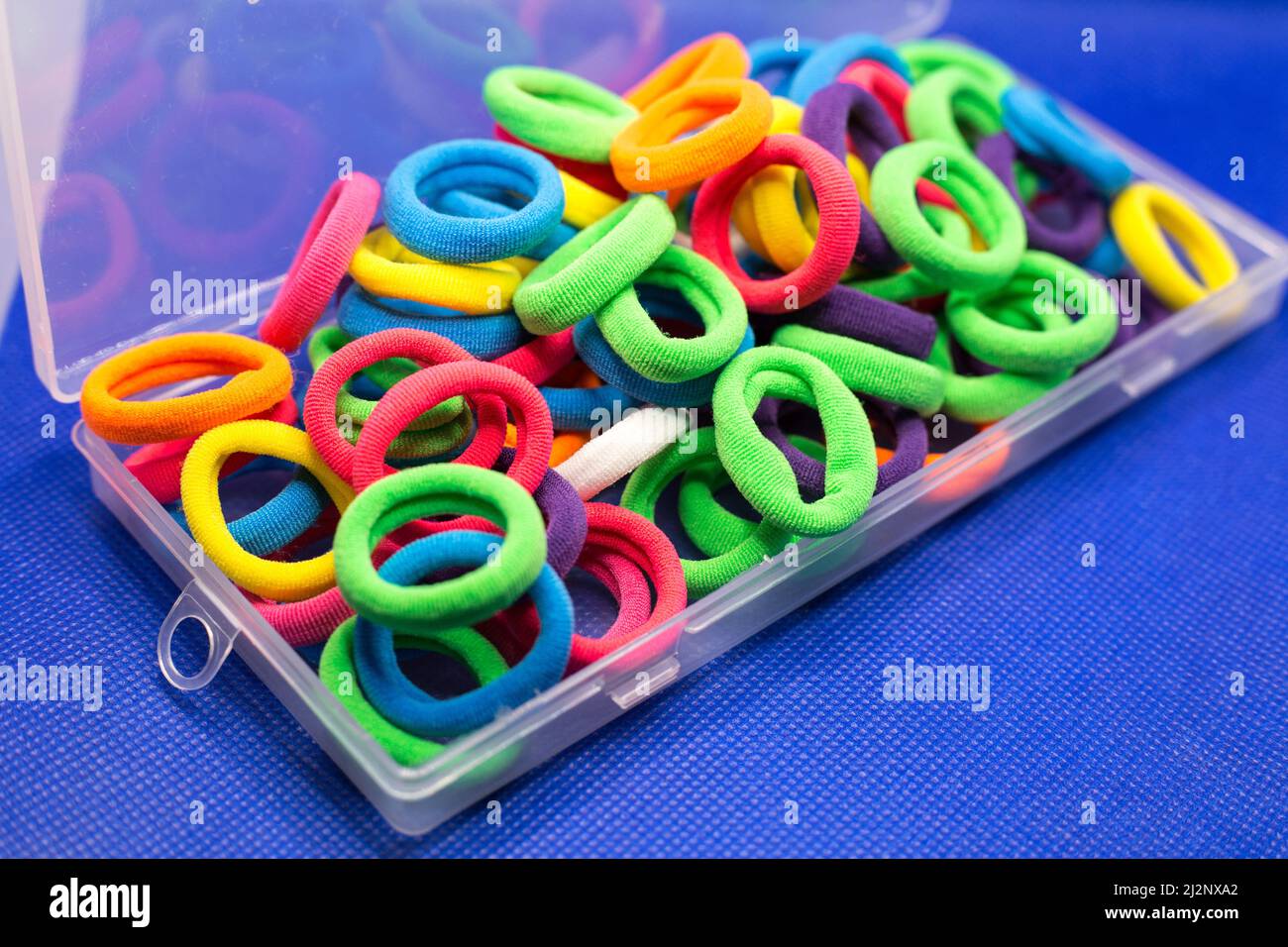 A set of bright multicolored hair bands in a transparent plastic box on ...