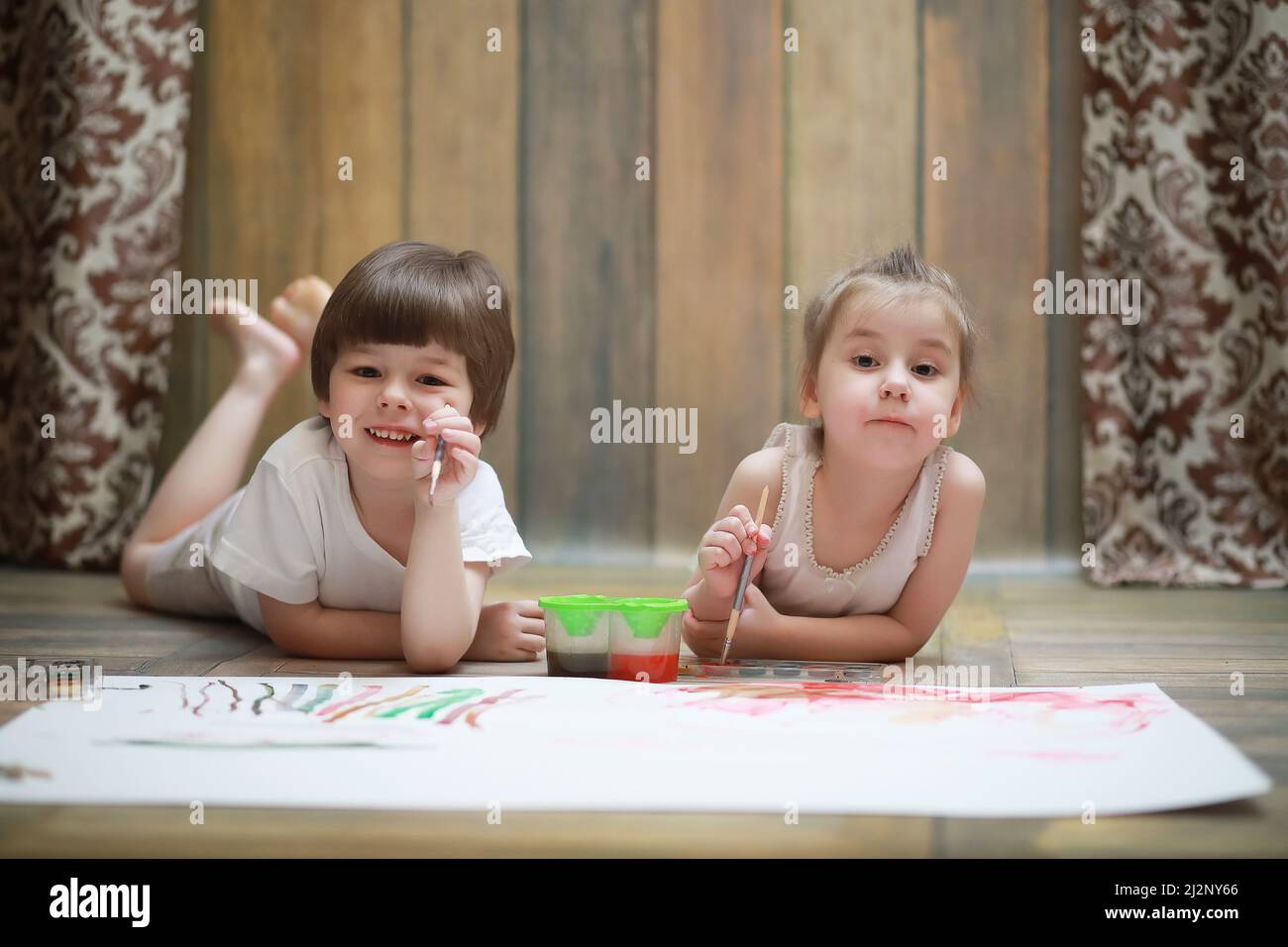Little children paint on a large sheet of paper on the floor Stock ...