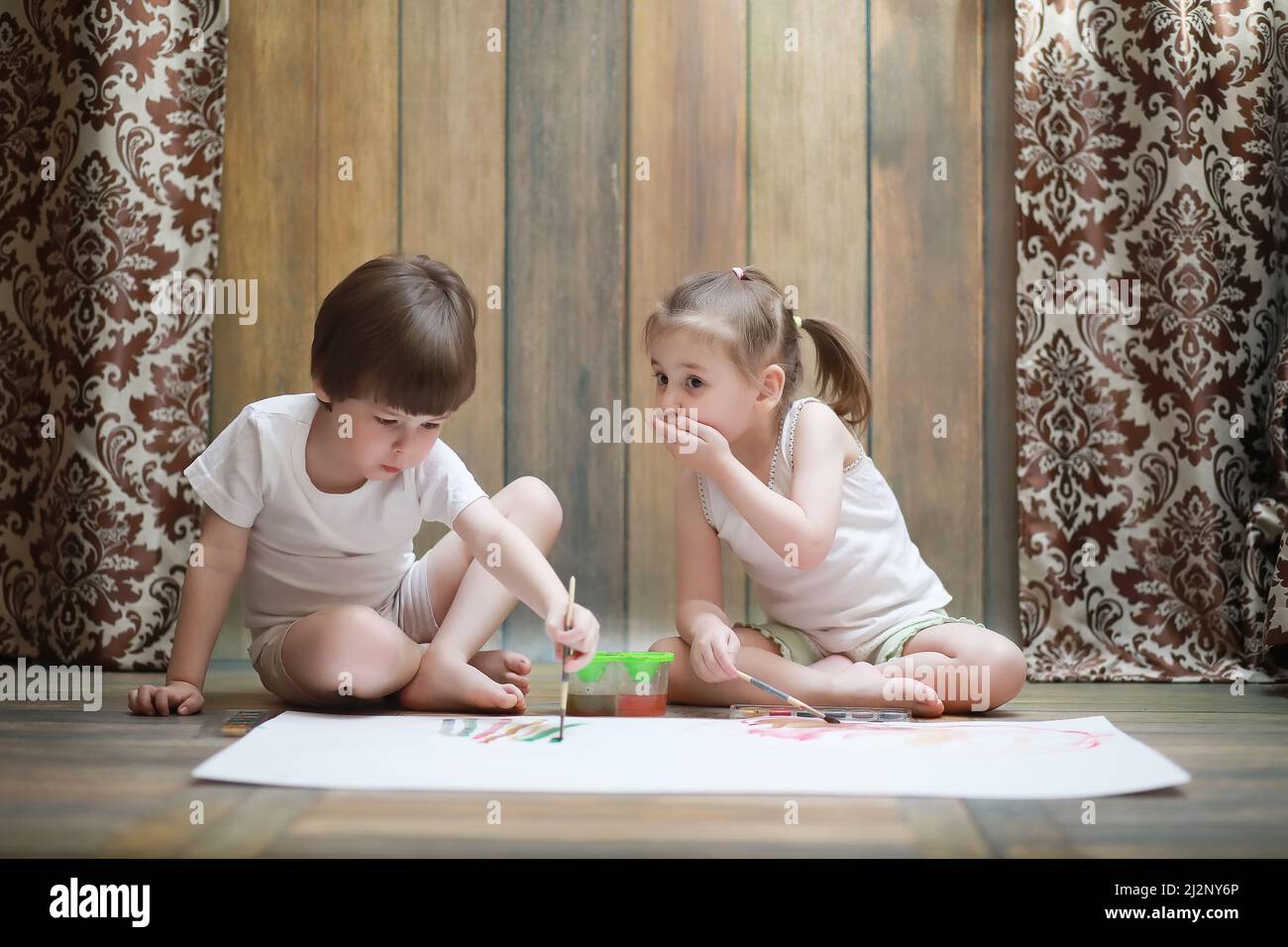 Little children paint on a large sheet of paper on the floor Stock ...