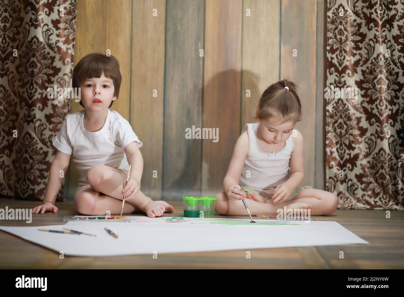 Little children paint on a large sheet of paper on the floor Stock ...