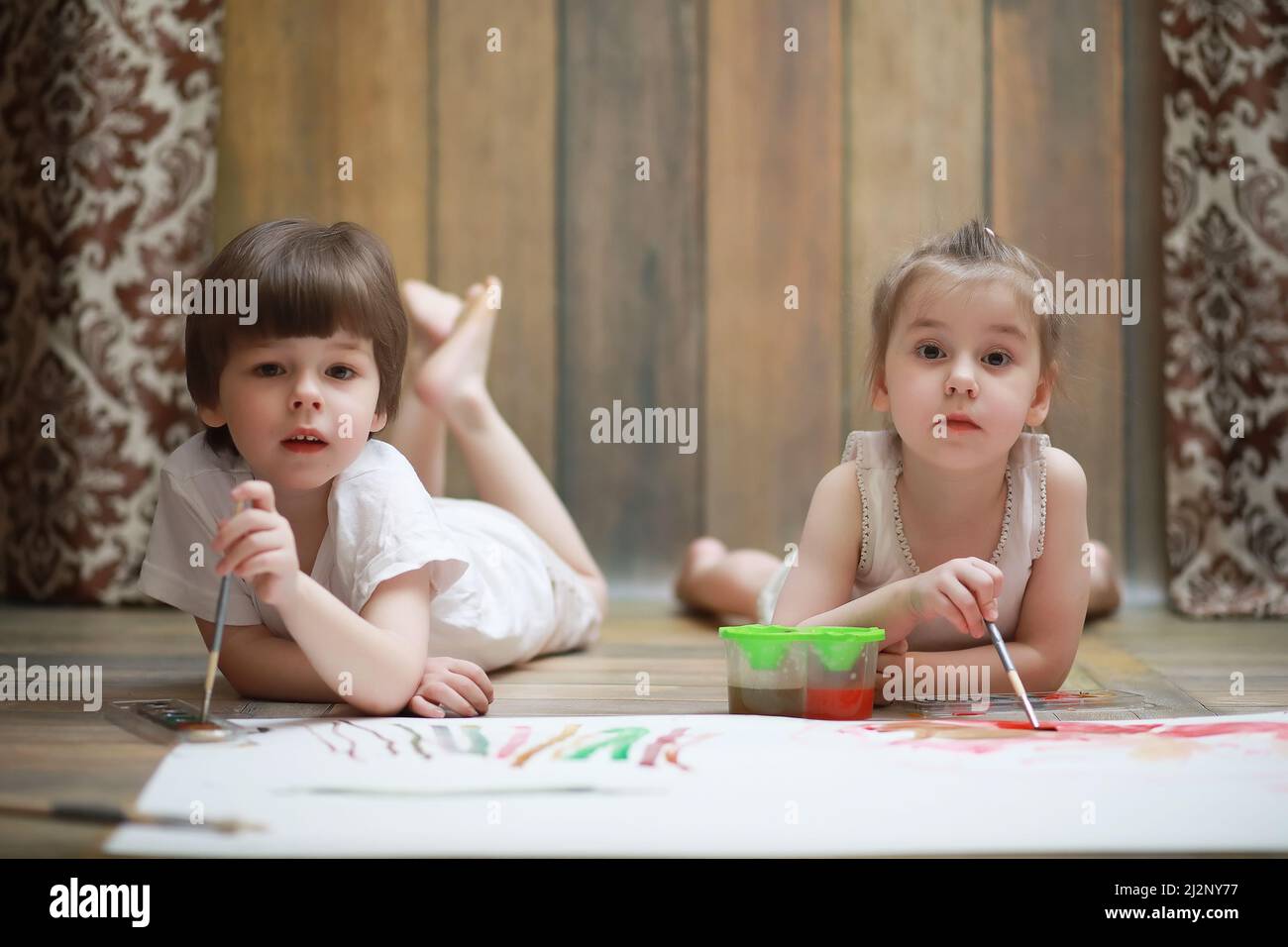 Little children paint on a large sheet of paper on the floor Stock ...