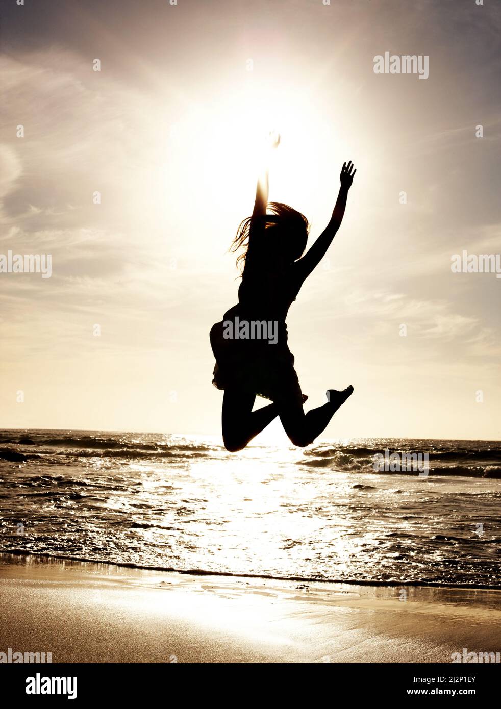 Happy young lady jumping on beach. Portrait of a pretty young lady ...