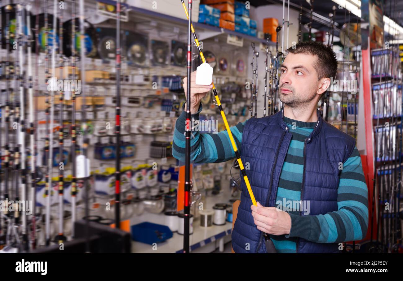 Fisherman customer looking new fishing rod Stock Photo - Alamy