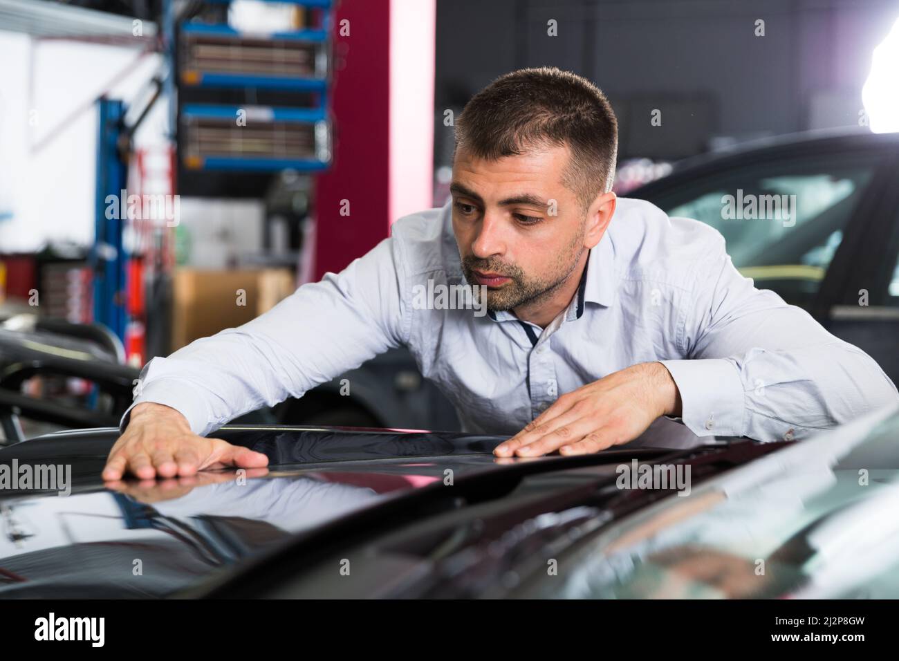 Male customer examining car body after repainting Stock Photo - Alamy