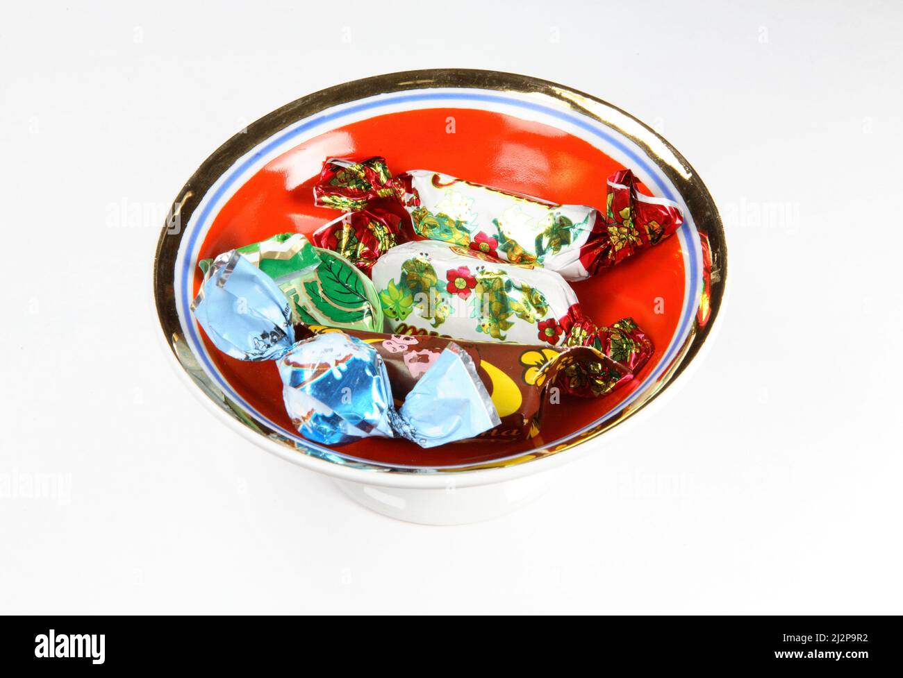 set of candies in sweet wrapper on red saucer Stock Photo - Alamy