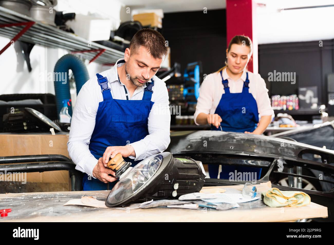 Professional mechanic performing polishing of headlight in automobile ...