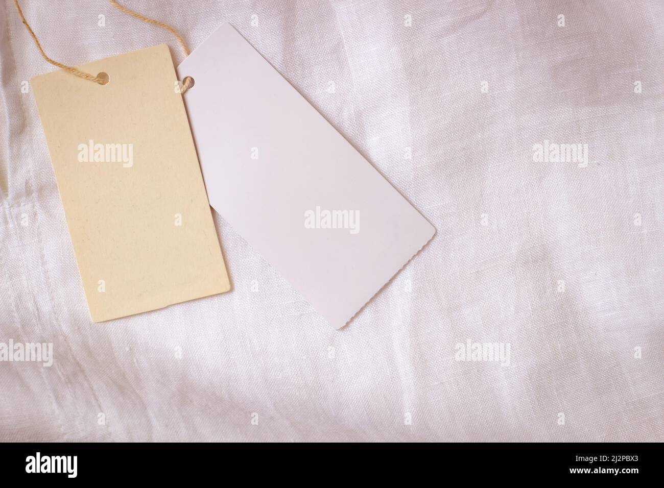 Blank price label tag paper card on white natural linen fabric shirt ...