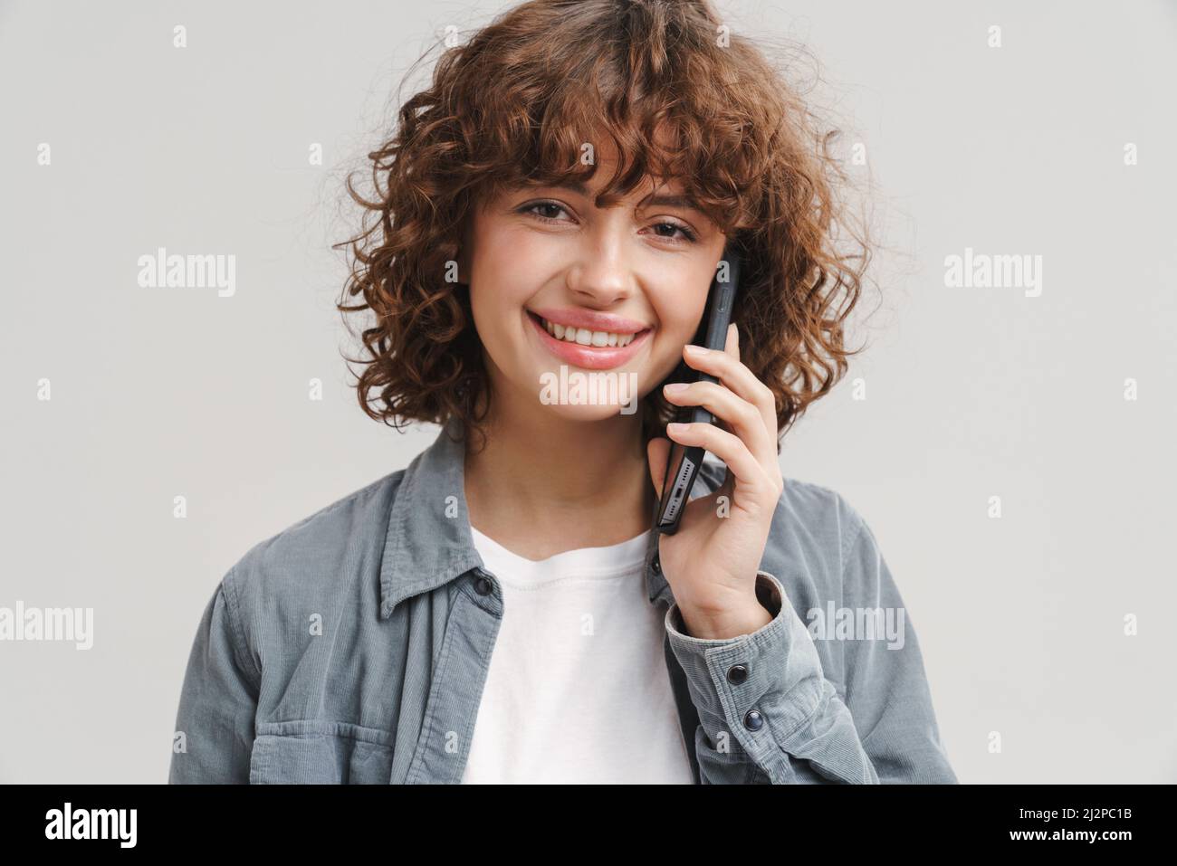 Young joyful woman smiling while talking on mobile phone isolated over ...