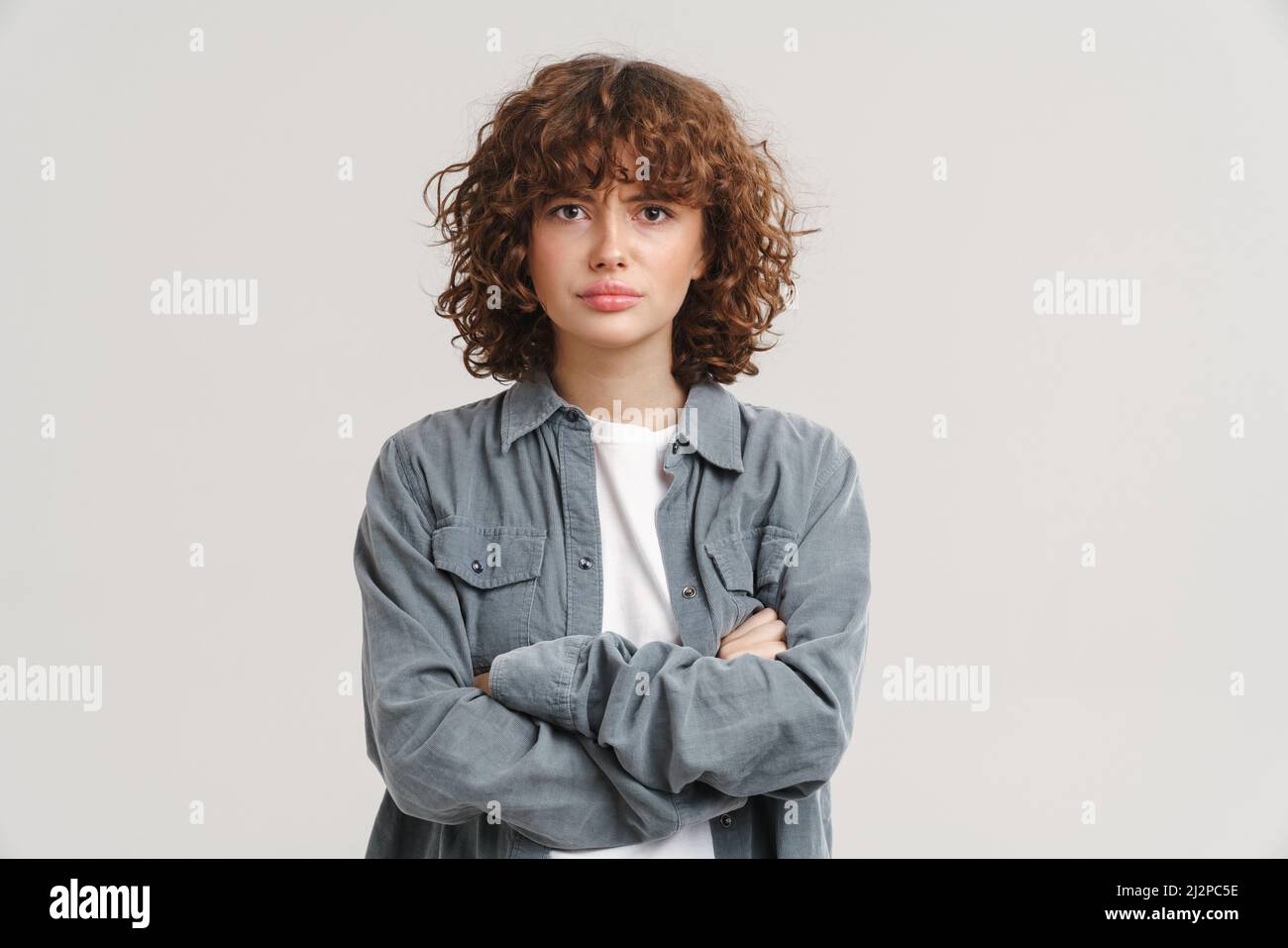 Young ginger serious woman posing with arms crossed isolated over white ...