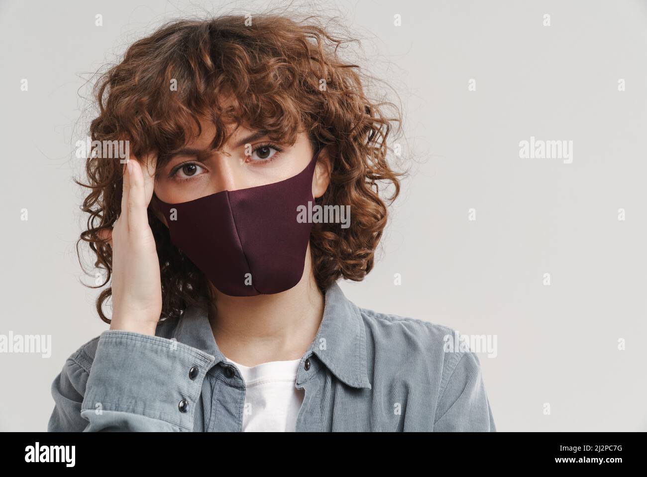 Ginger woman in face mask with headache rubbing her temple isolated ...