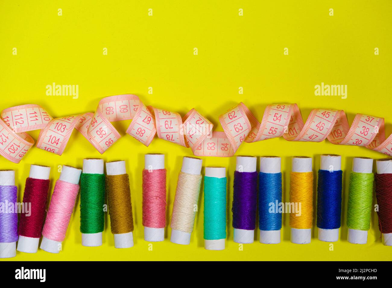 A set of multi-colored threads for sewing and a measuring tape on a ...