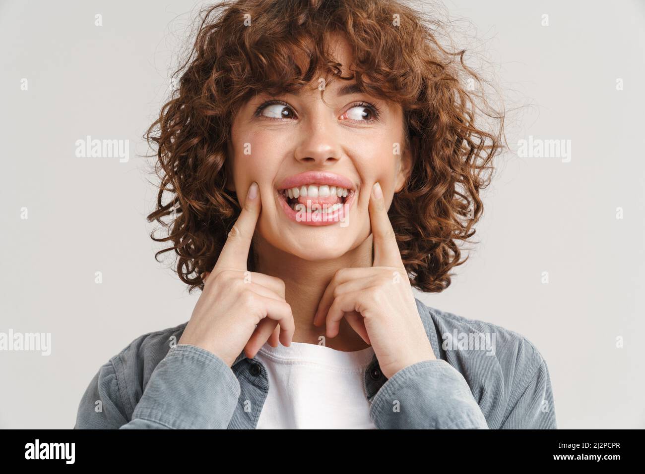 Ginger joyful woman showing her tongue and pointing fingers at her ...