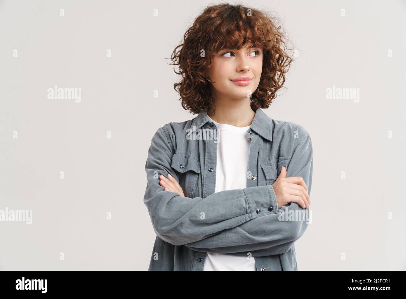 Young ginger pleased woman posing with arms crossed isolated over white ...
