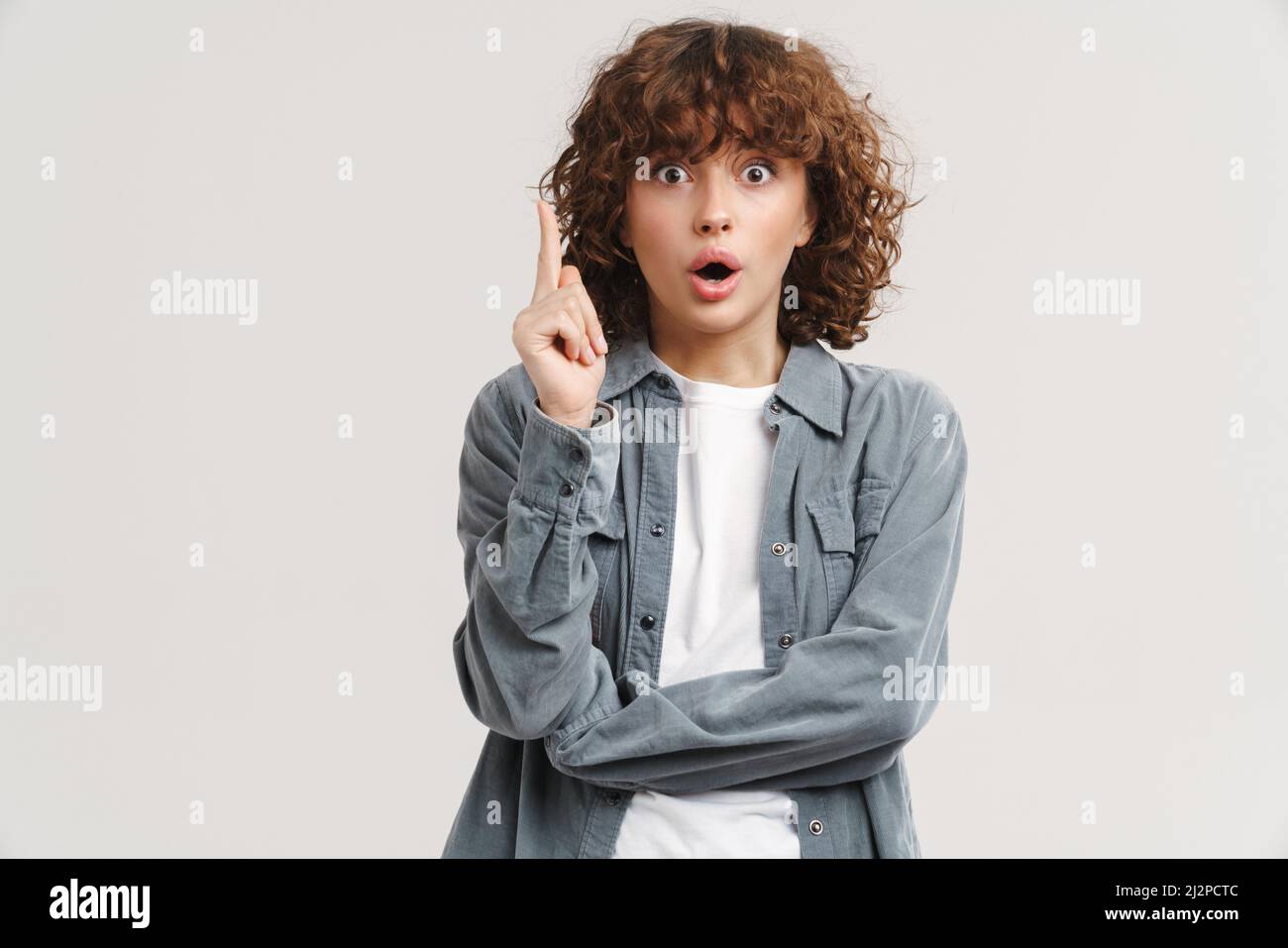 Young ginger shocked woman exclaiming while pointing finger upward ...