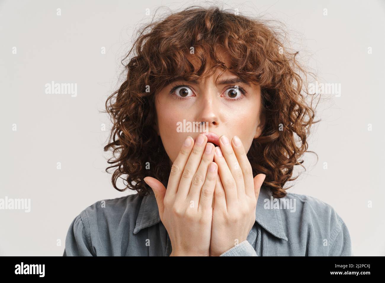 Young ginger shocked woman expressing surprised and covering her moth ...