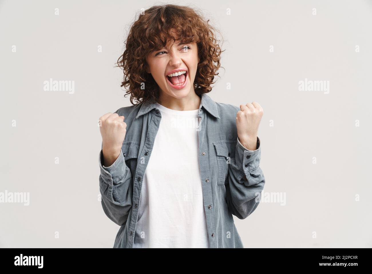 Young ginger excited woman screaming and making winner gesture isolated ...