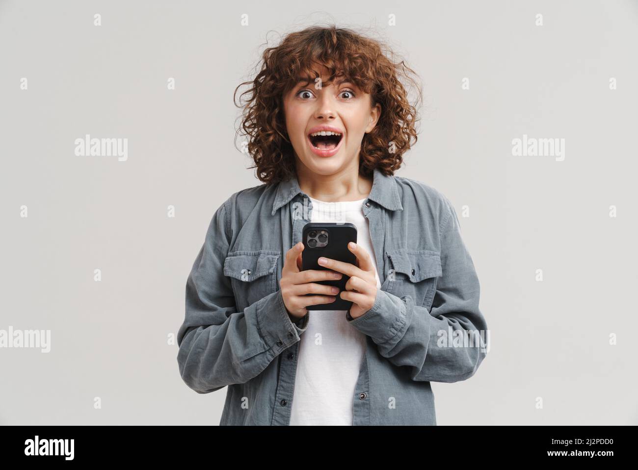 Young red surprised woman exclaiming while using mobile phone isolated ...