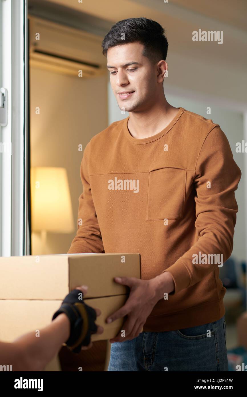 Positive young man receiving boxes delivered by courier Stock Photo - Alamy