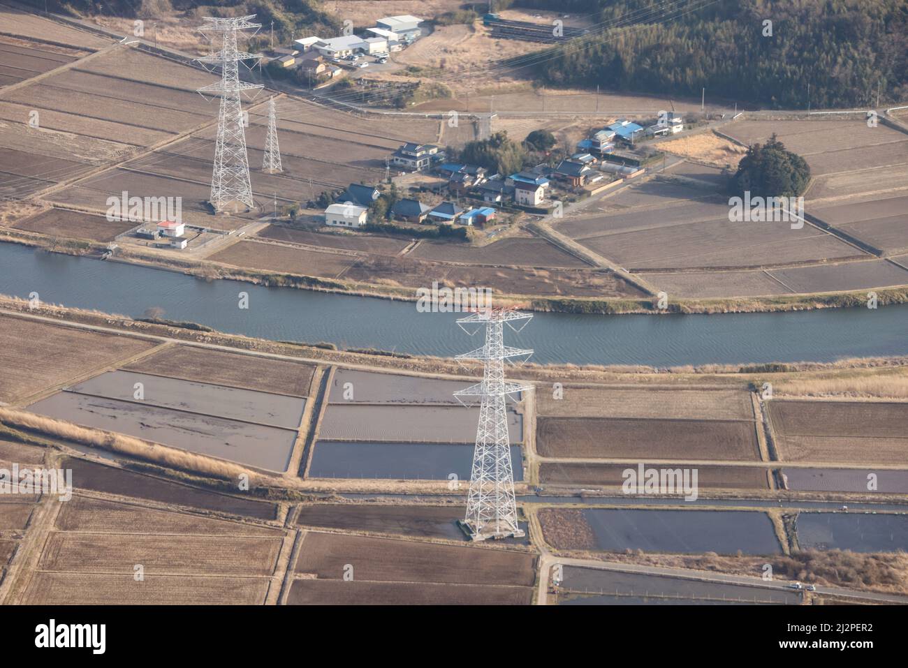 Electrical towers over river between farms and fields Stock Photo - Alamy