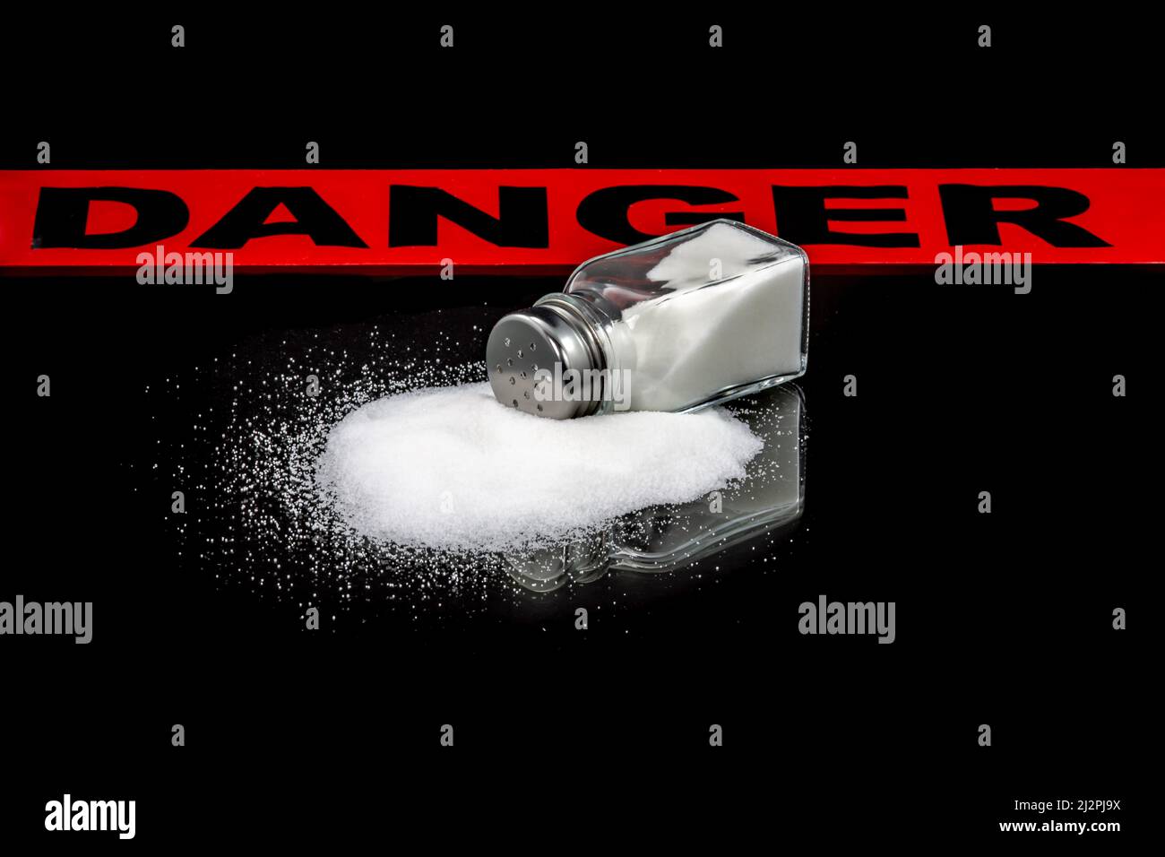 Danger banner with salt shaker on the side and salt spilling on a black ...