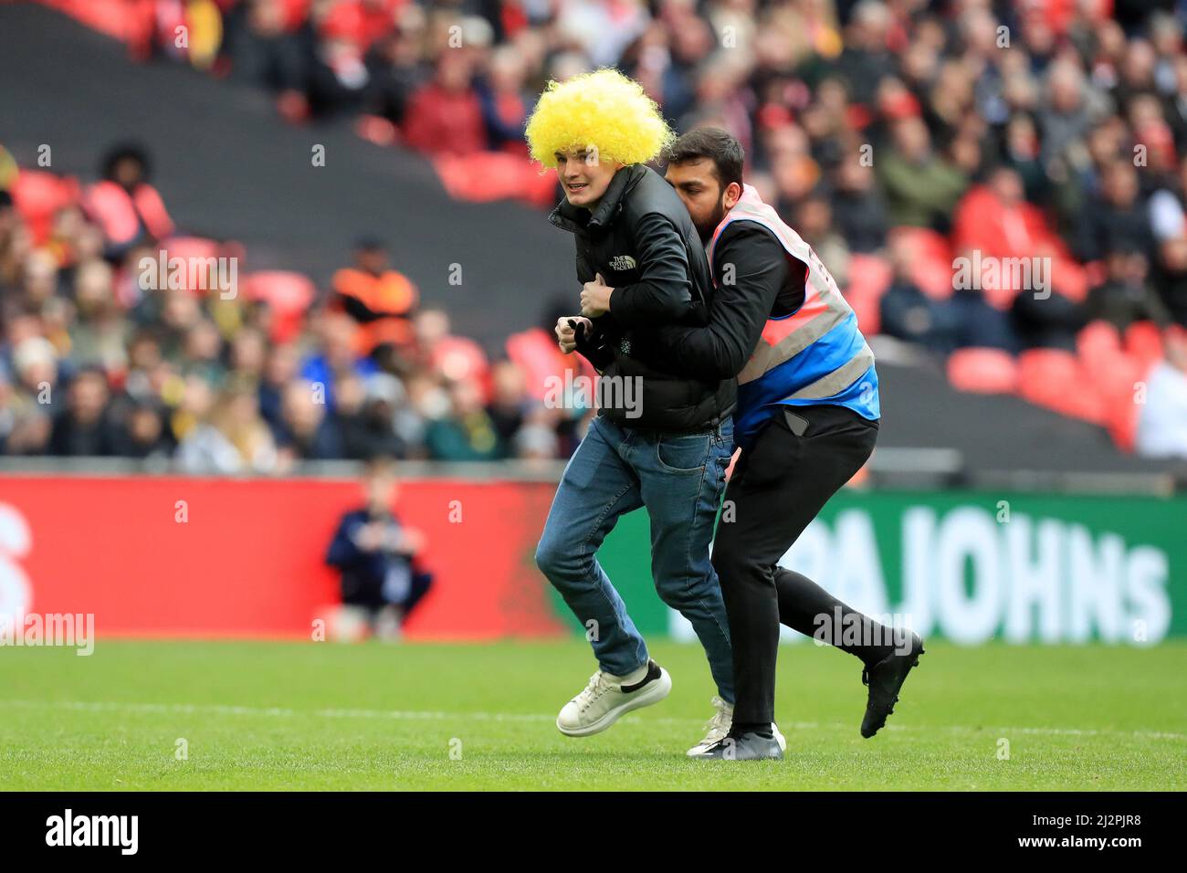 A steward apprehends the Sutton United fan on the pitch Stock Photo - Alamy