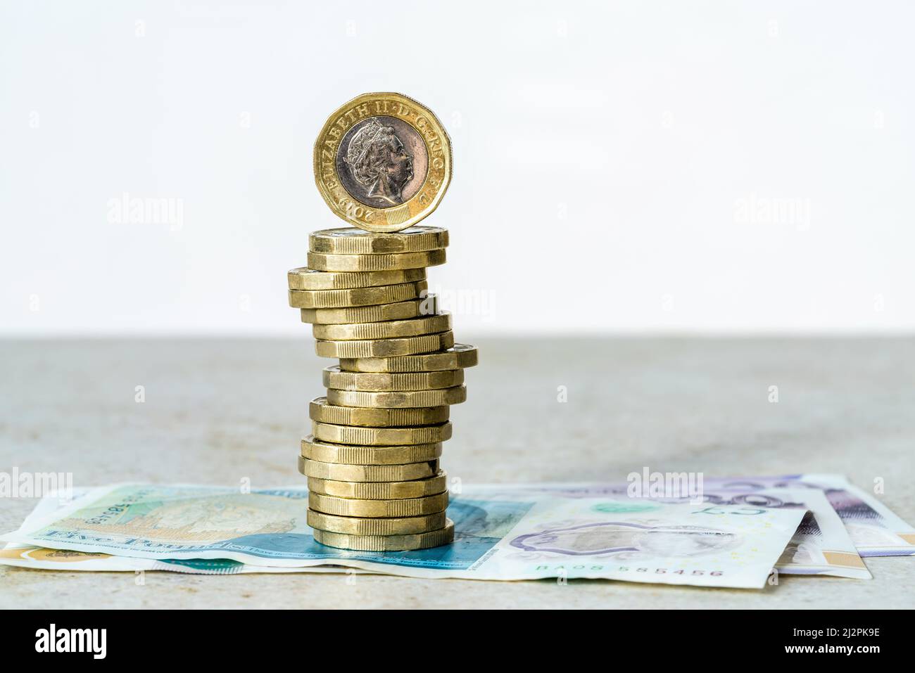 Money - a stack of £1 coins and a jar of coins in the background ...