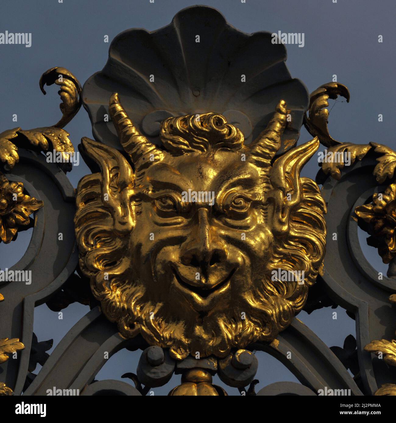 Square detail of grinning golden satyr mask with pointed ears and horns ...