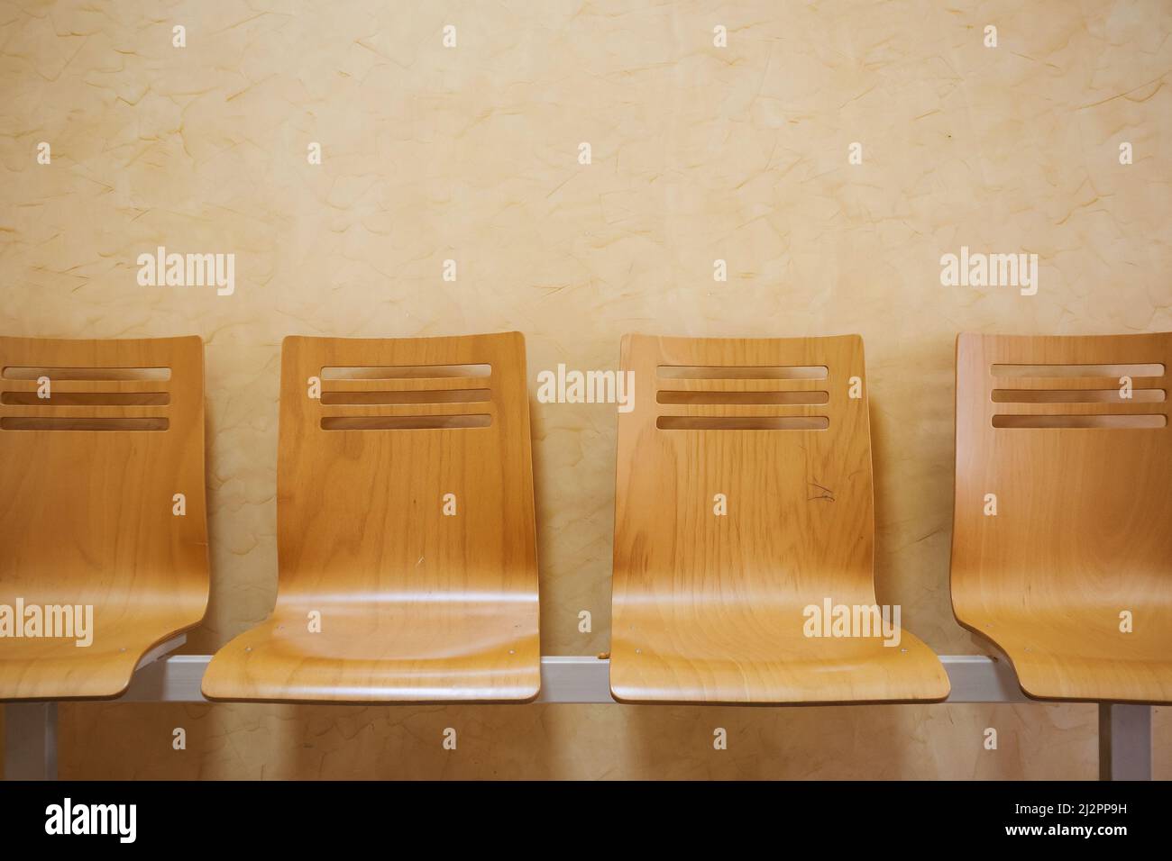 Wooden empty chairs in front of the wall, part of the waiting room ...