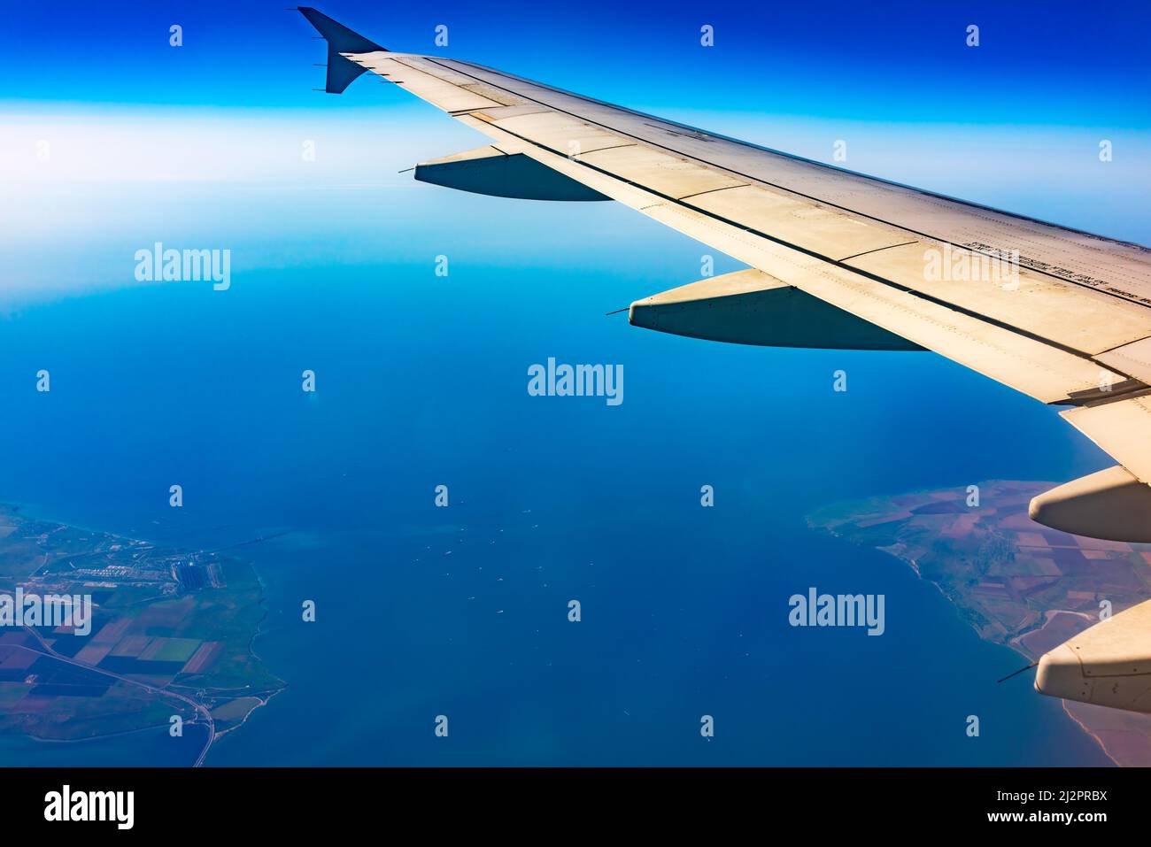 View from the airplane window at a beautiful blue clear sky, earth, sea ...