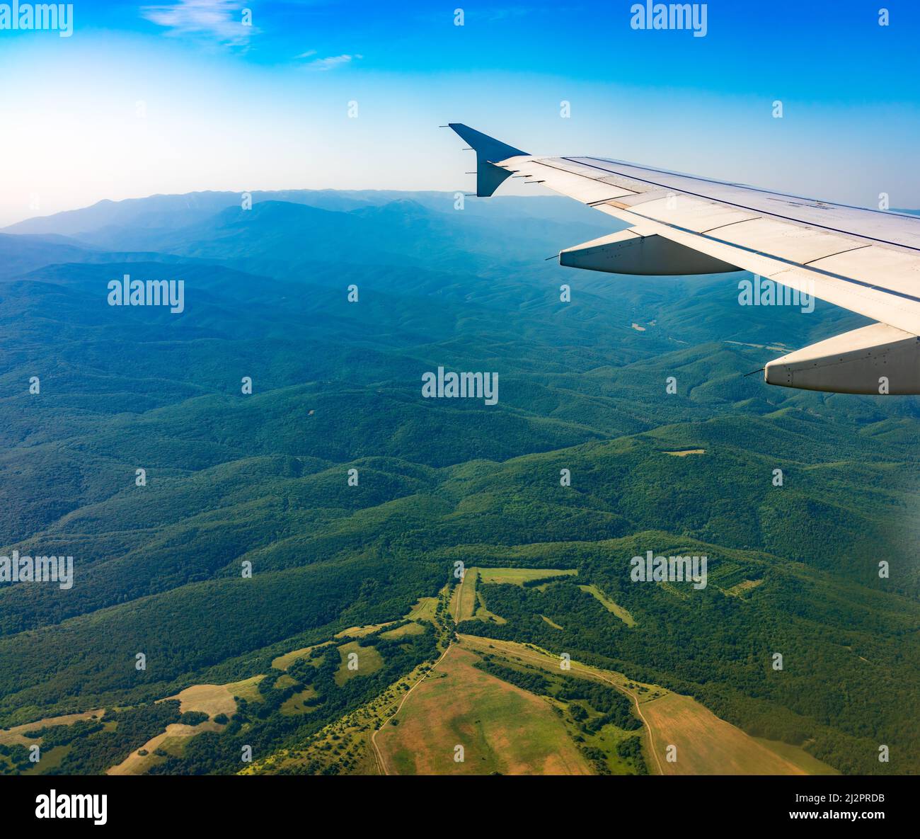 View of airplane wing, blue skies and green land during landing ...